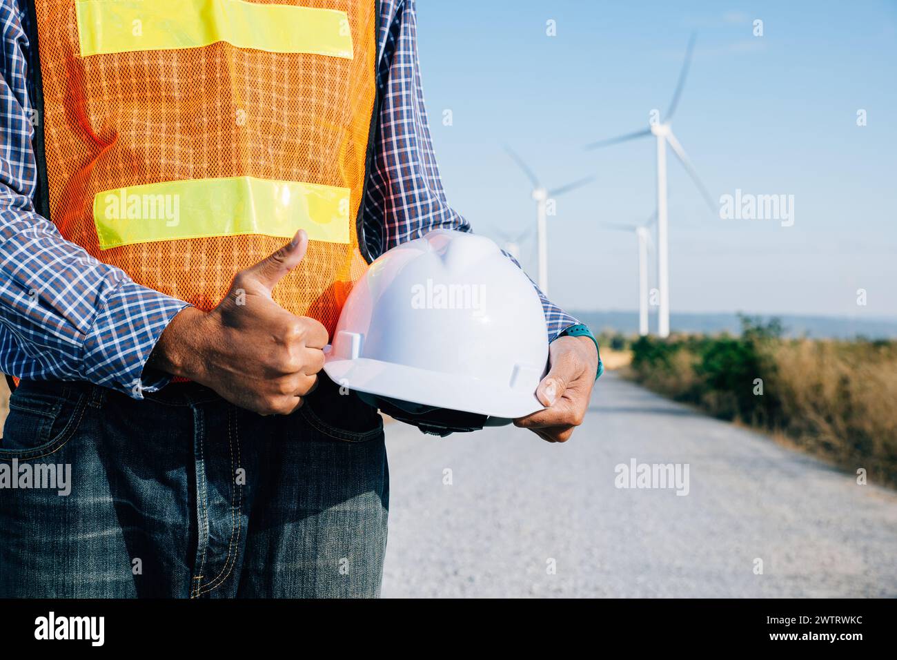 Engineer holding safety helmet stands at windmill field Stock Photo - Alamy