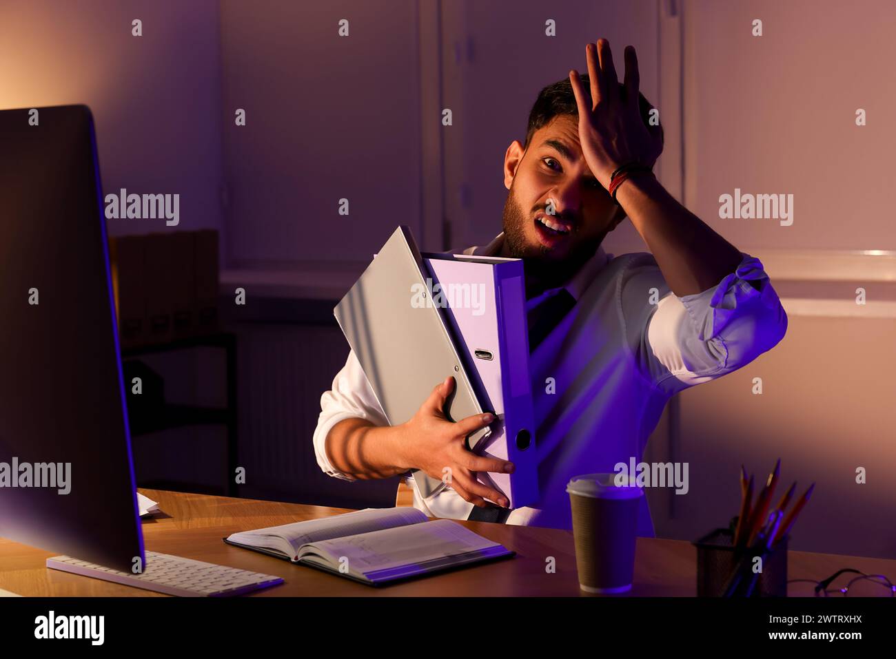 Tired young man working late in office Stock Photo - Alamy