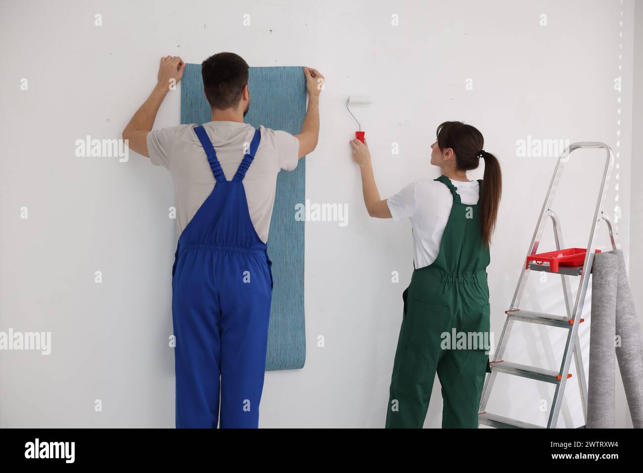 Workers hanging light blue wallpaper in room Stock Photo - Alamy
