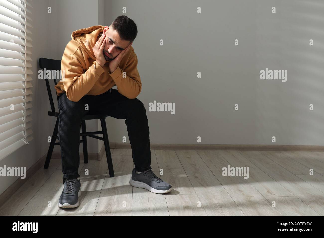Sad man sitting on chair near window. Space for text Stock Photo - Alamy