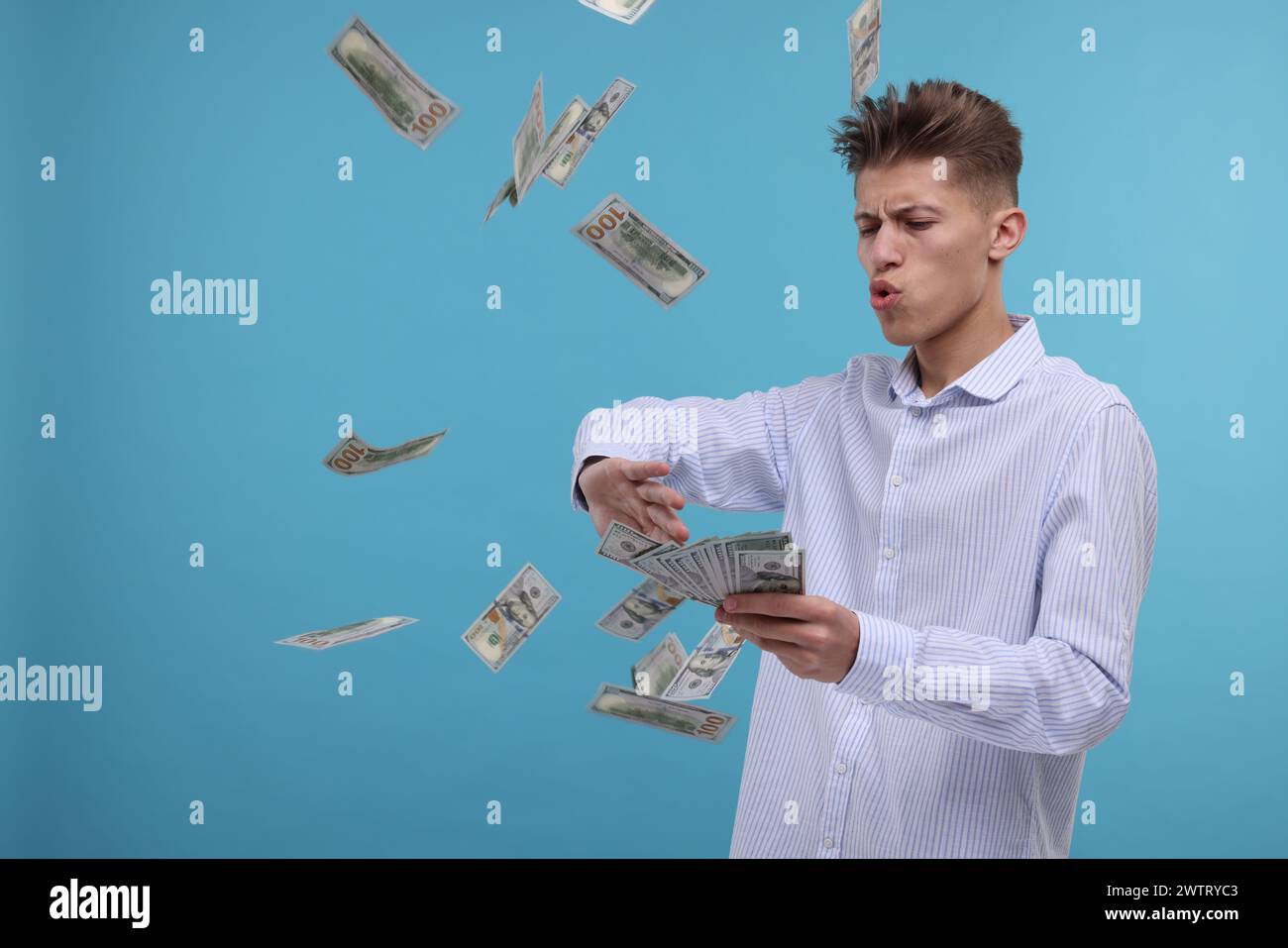 Handsome man throwing dollar banknotes on light blue background Stock ...