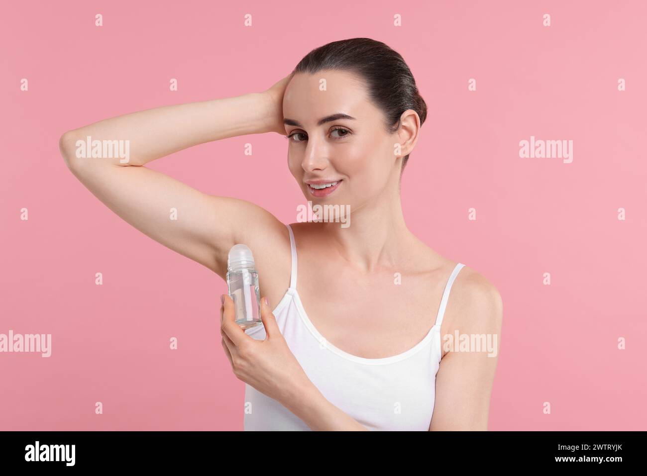 Beautiful woman applying deodorant on pink background Stock Photo - Alamy