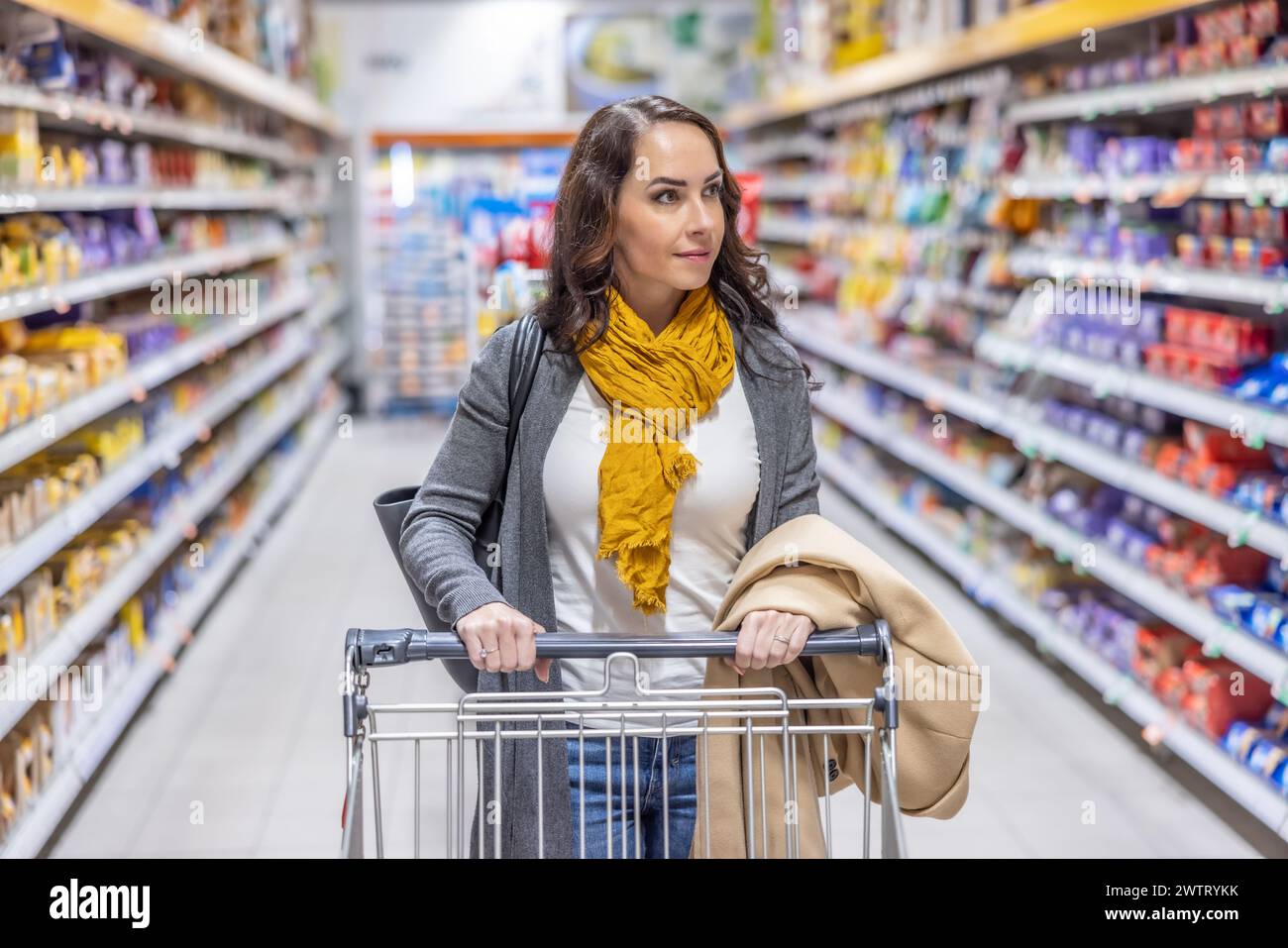 Young woman doing grocery shopping at the supermarket, she is pushing a ...