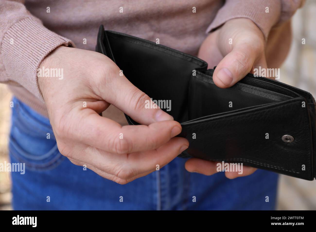 Poor man holding empty wallet outdoors, closeup Stock Photo - Alamy