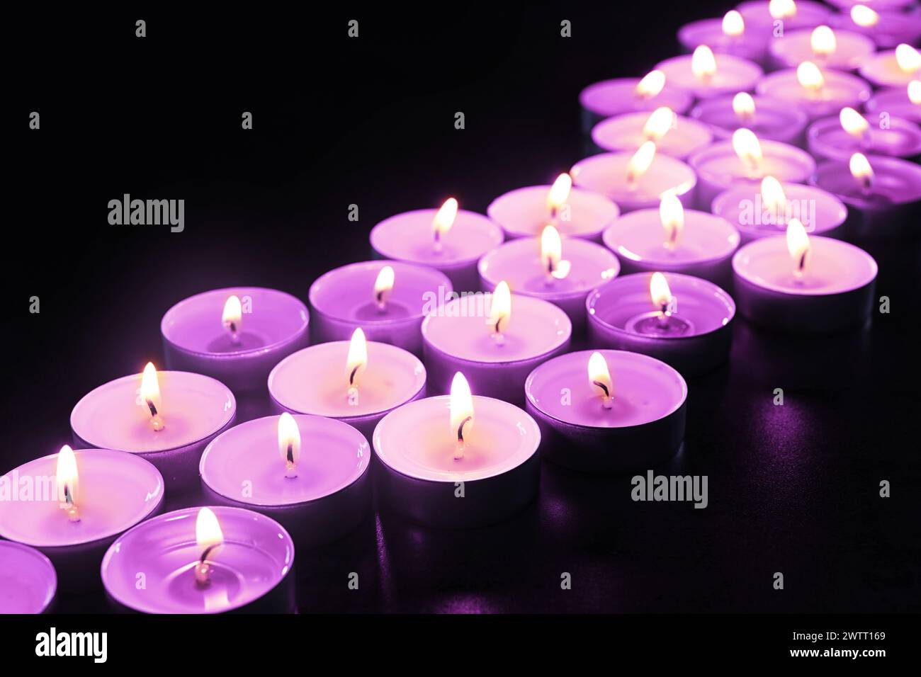 Beautiful burning violet candles on black background. Funeral ...