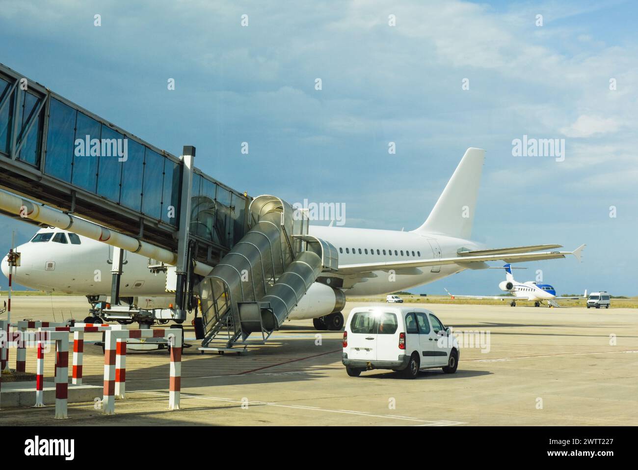 Passenger plane on runway with boarding tunnel and stairs before take ...