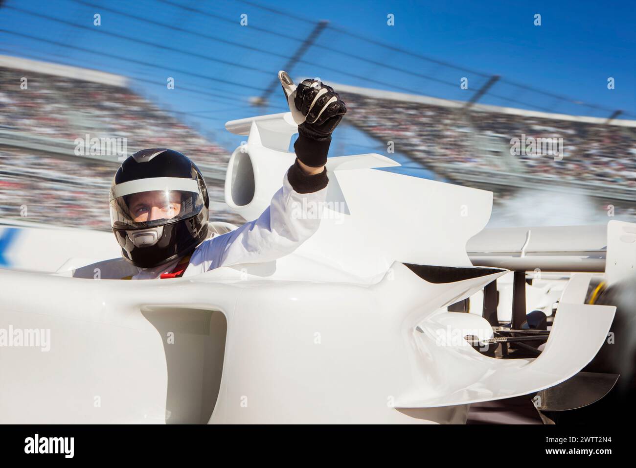Race car driver in helmet giving a thumbsup from cockpit on racetrack ...