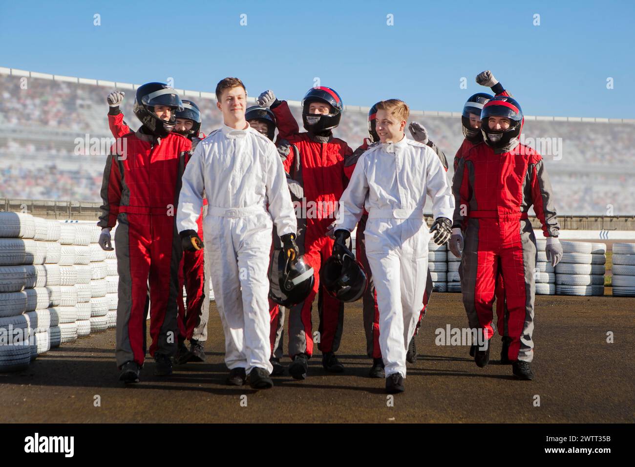 A group of smiling friends geared up for gokart racing on a bright ...