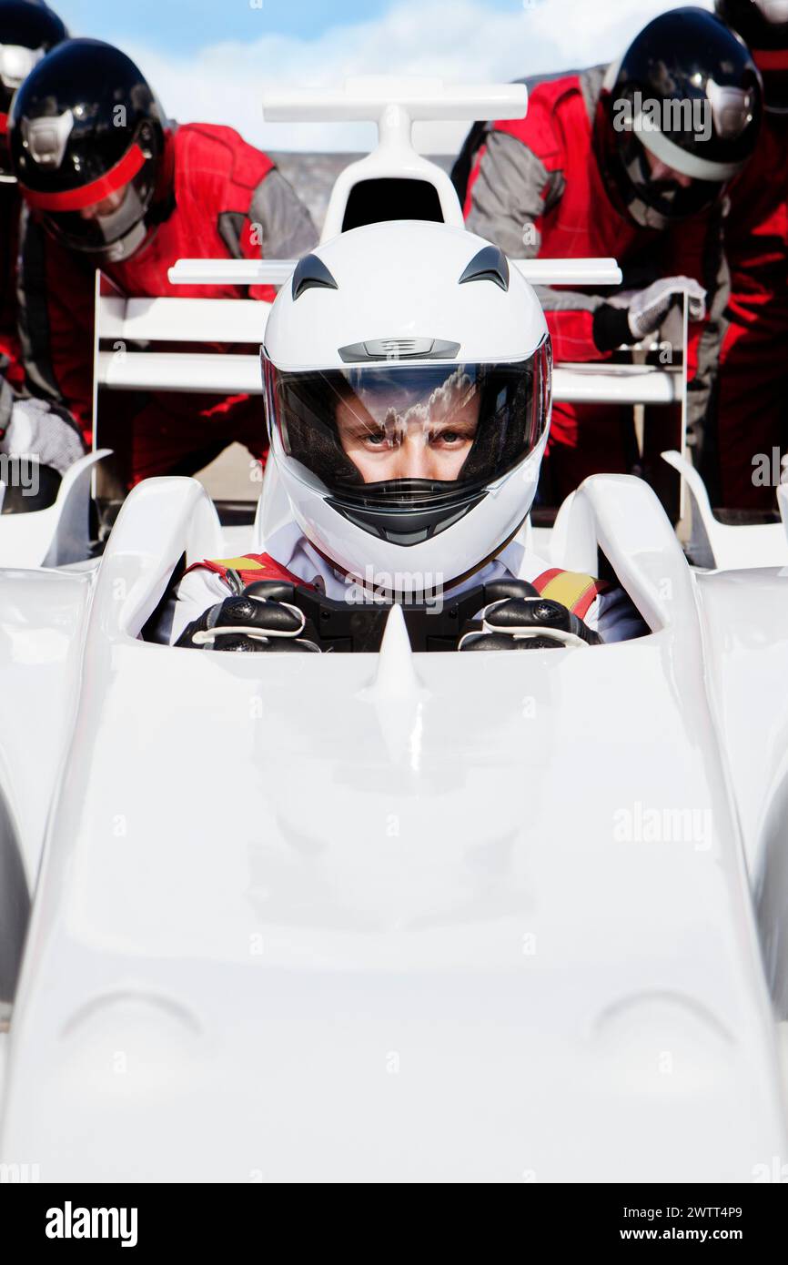 Focused driver gearing up with racing team in the background Stock ...