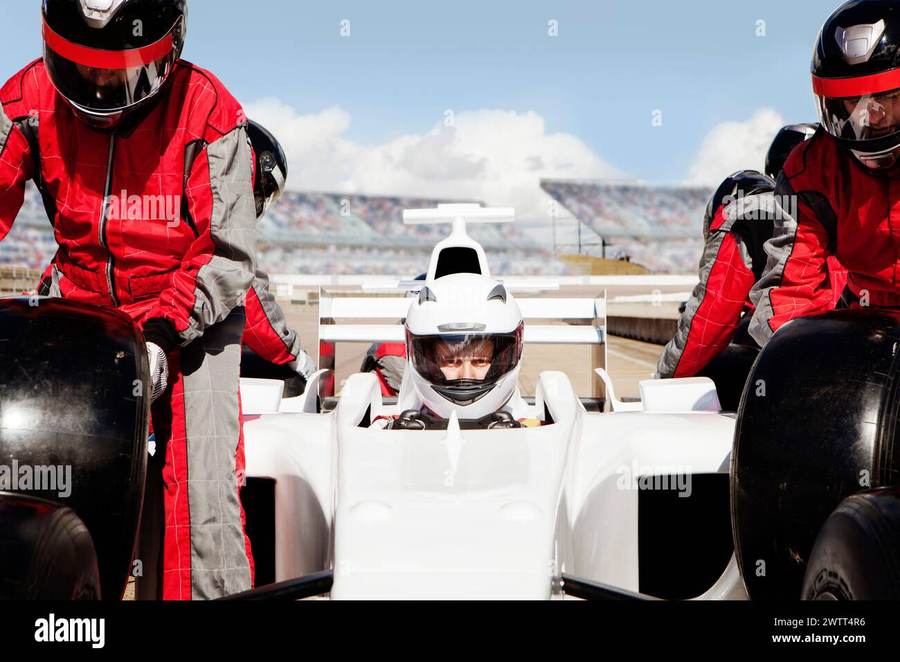 Intense focus from a racing driver getting ready in the cockpit, assisted by the pit crew Stock ...