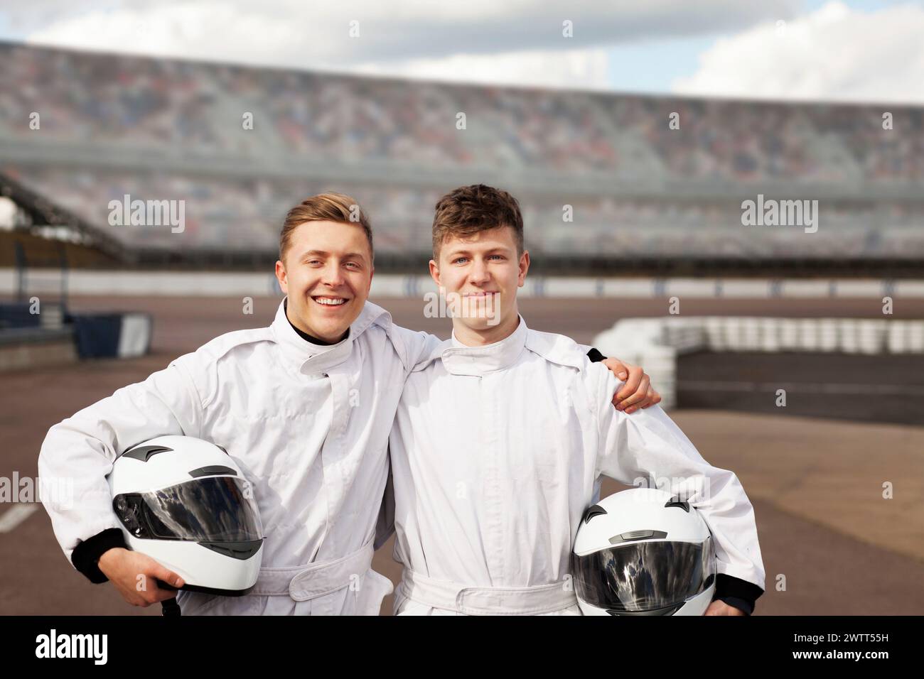 Two happy drivers at the racetrack with helmets Stock Photo - Alamy