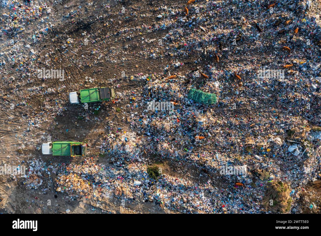 Aerial top down view of garbage trucks unload pile of waste at landfill ...