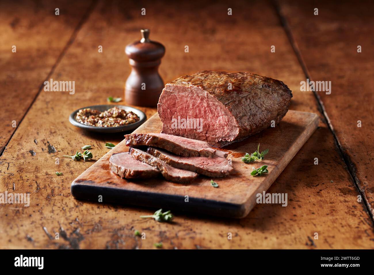Succulent medium rare beef roast on a rustic wooden board with ...