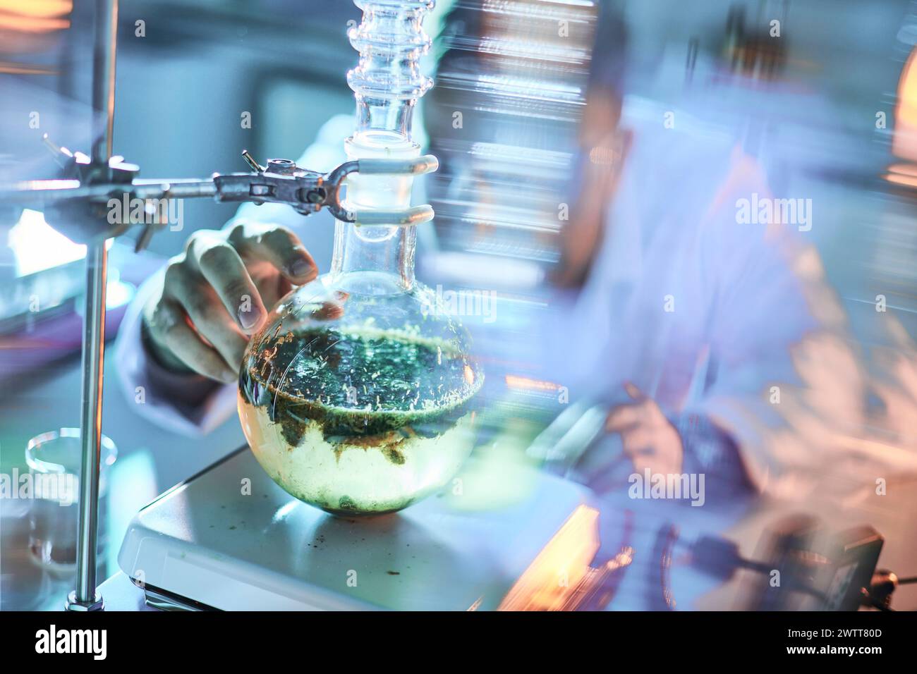 Labratory scientist extracting material for testing from beaker under ...