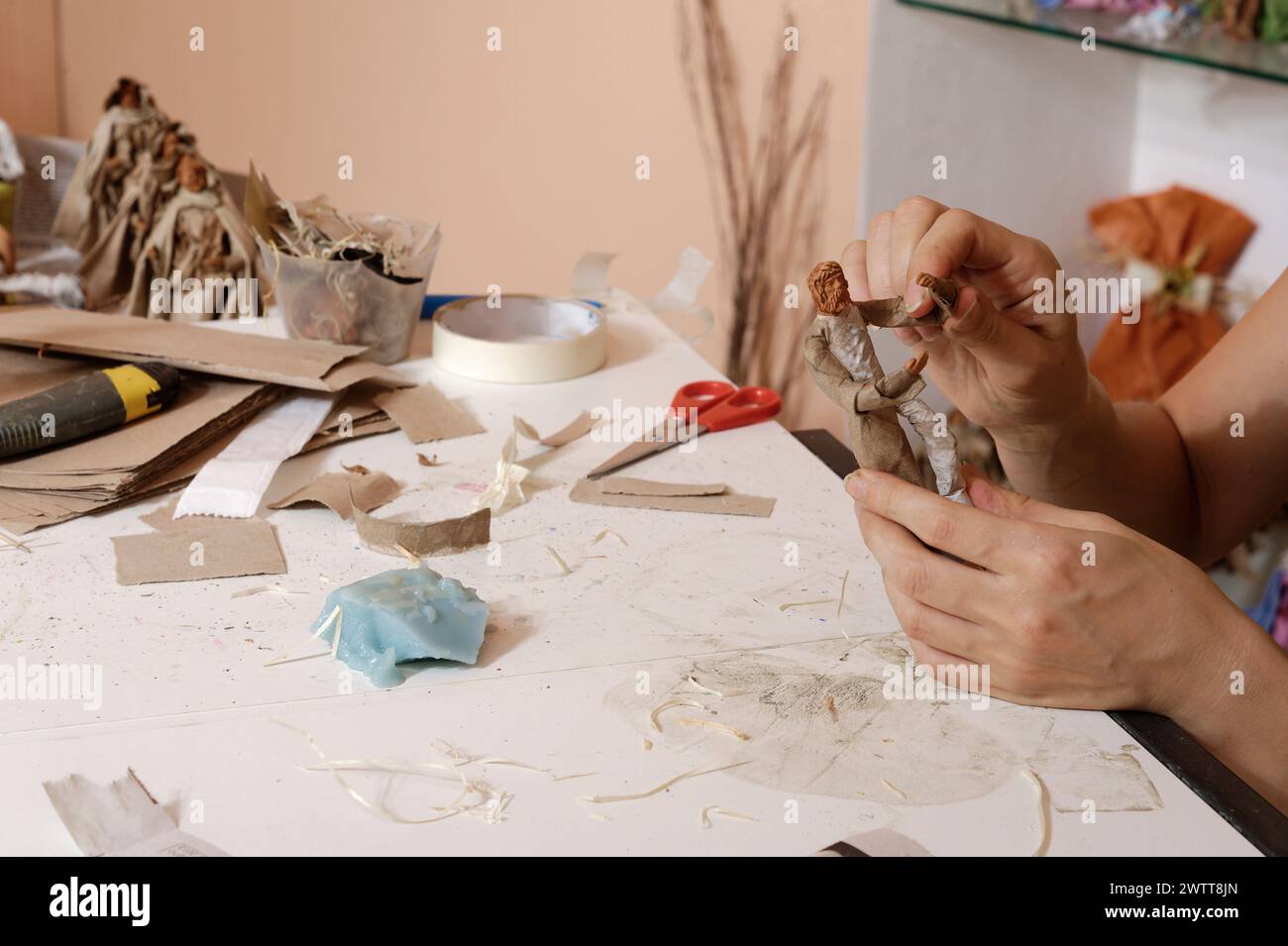 Crafting hands meticulously shaping an object amid a table full of ...