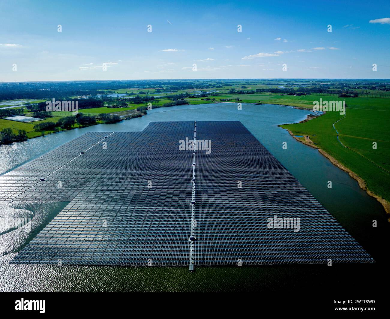 A vast solar farm sprawling across the landscape under a clear blue sky ...