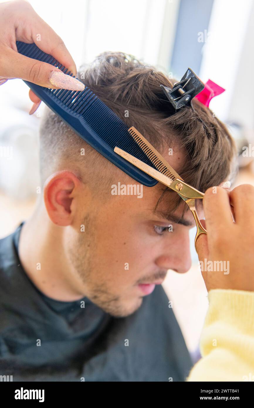 Barber in action giving a detailed trim to a young man's hair Stock ...