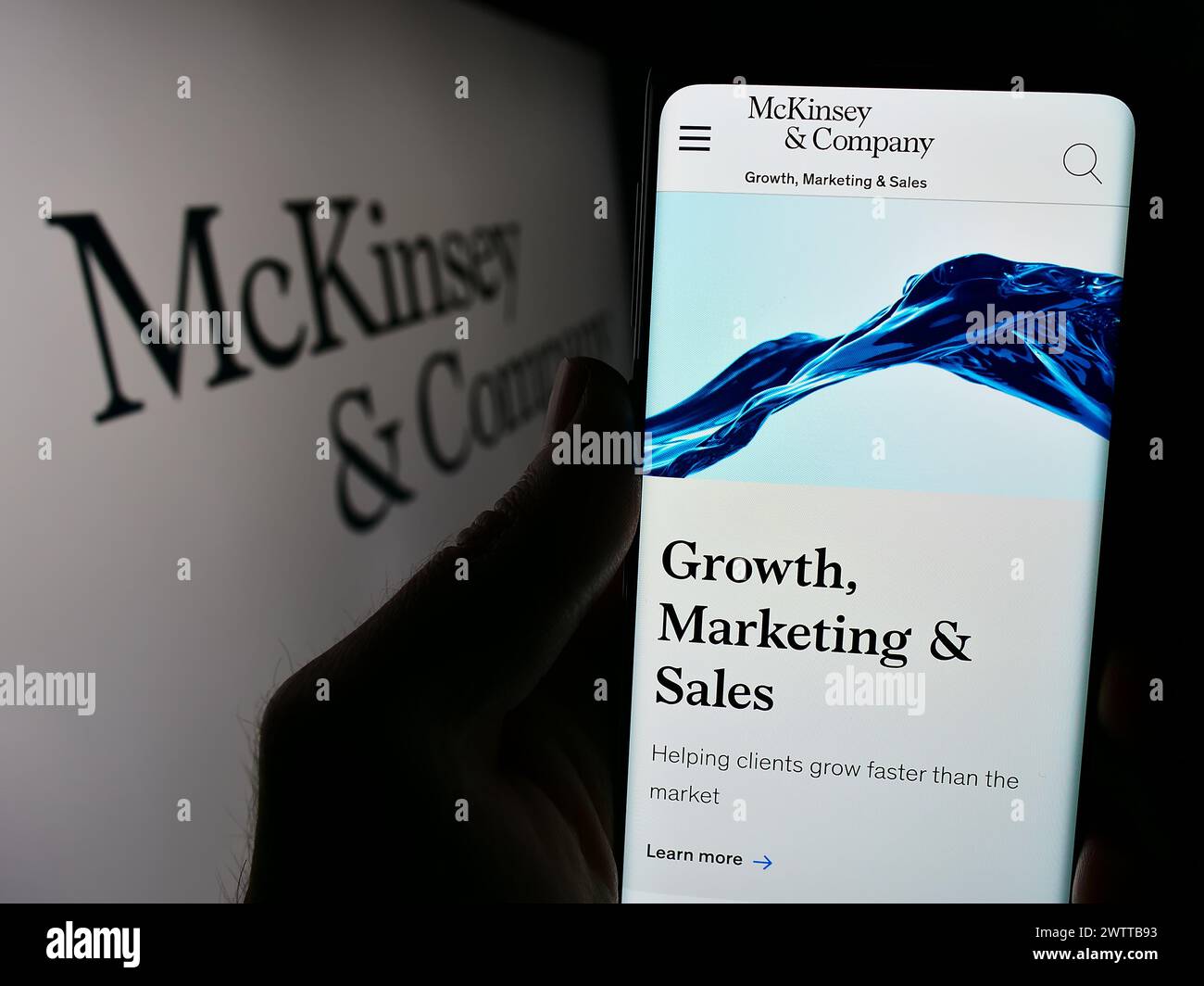 Person holding cellphone with webpage of US consulting business ...