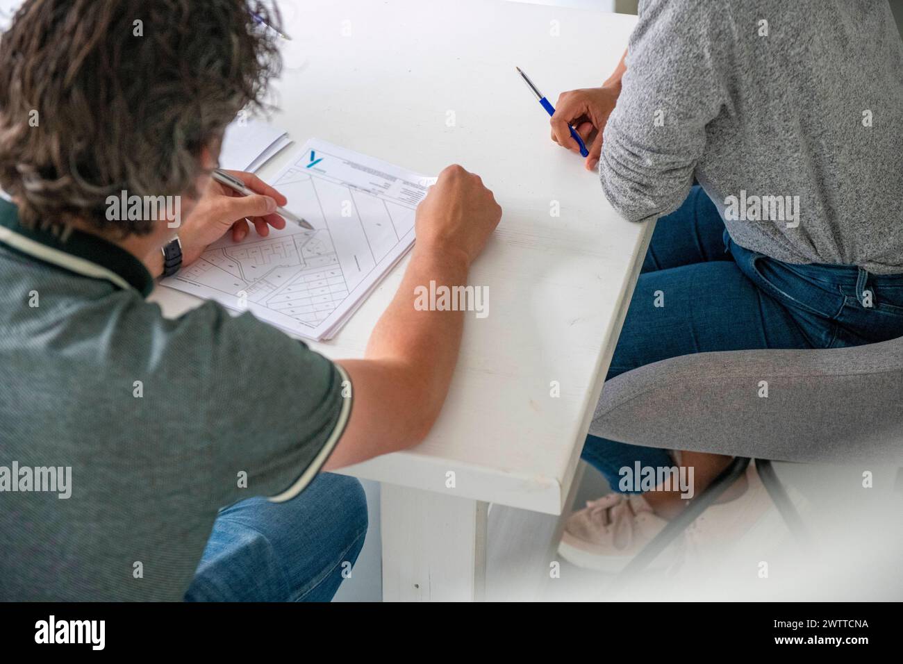 Two people collaborating on a project at a white table Stock Photo - Alamy
