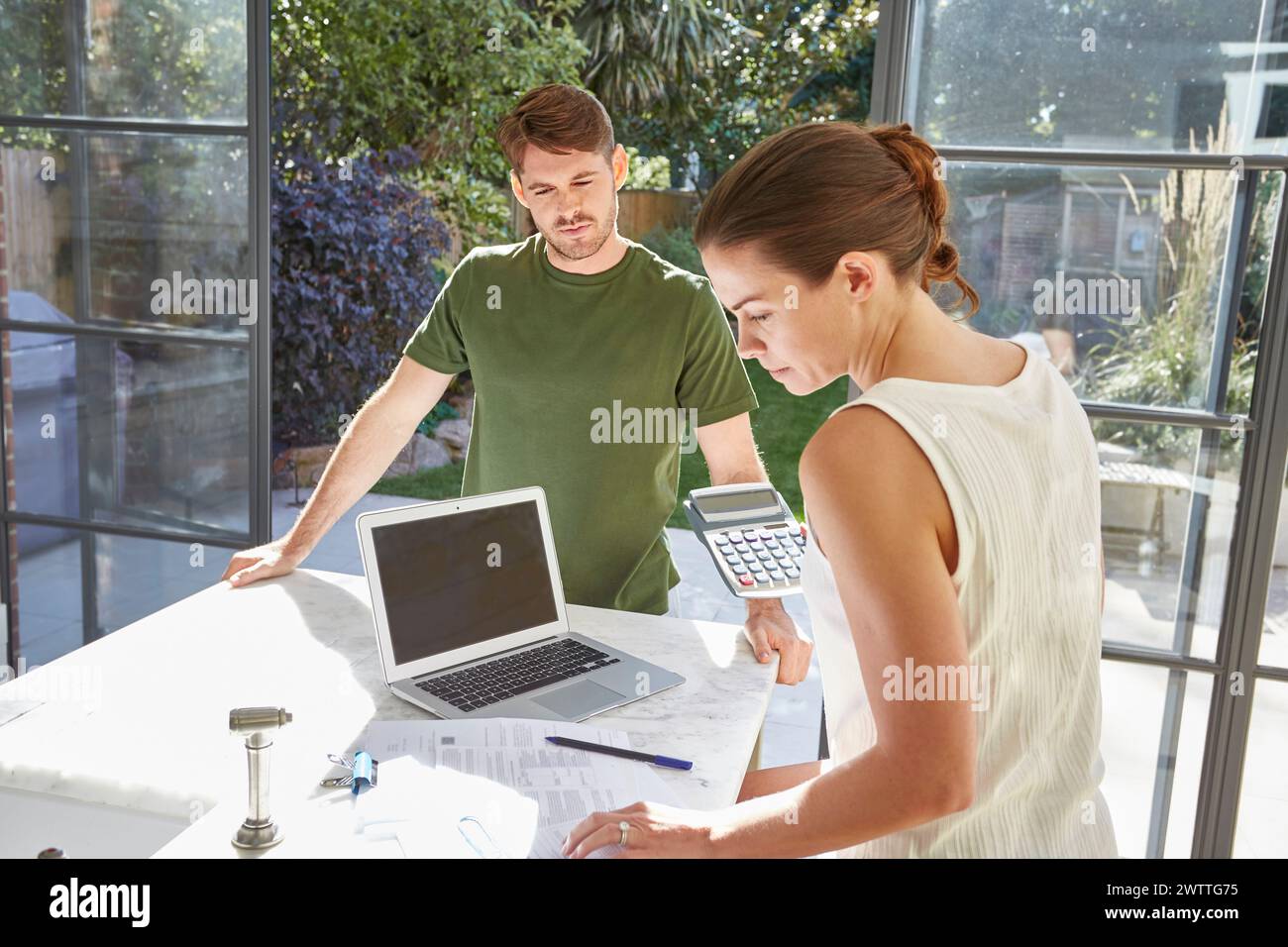 Two people working together at a table with a laptop Stock Photo - Alamy