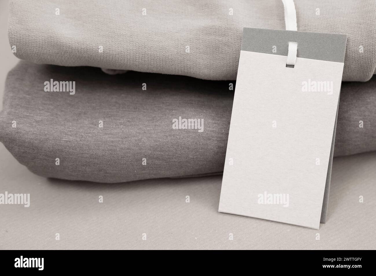 Garment with cardboard tag on kraft paper sheet, closeup. Space for ...