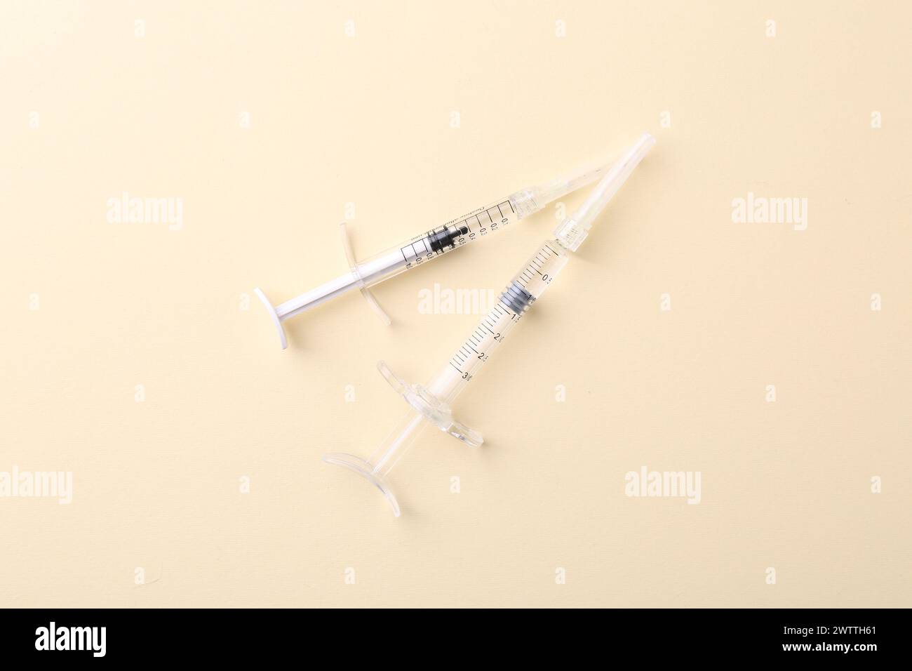 Injection cosmetology. Two medical syringes on beige background, top ...