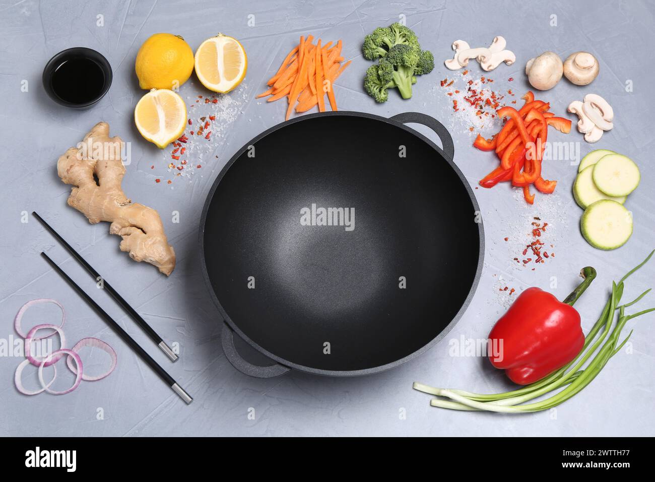 Wok, chopsticks and different products on grey table, above view Stock ...
