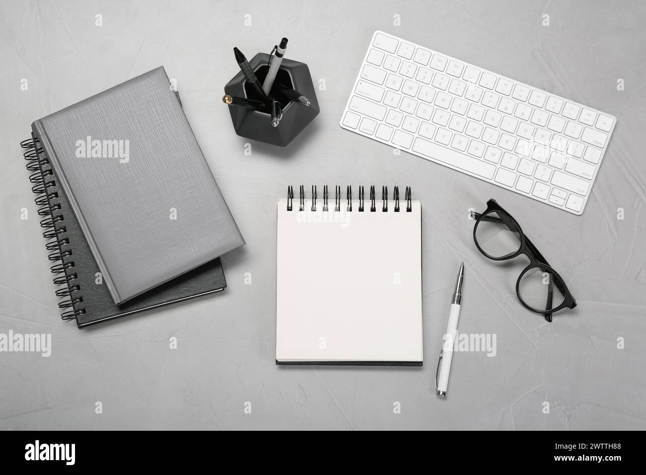 Flat lay composition with notebooks, keyboard and glasses on light grey ...