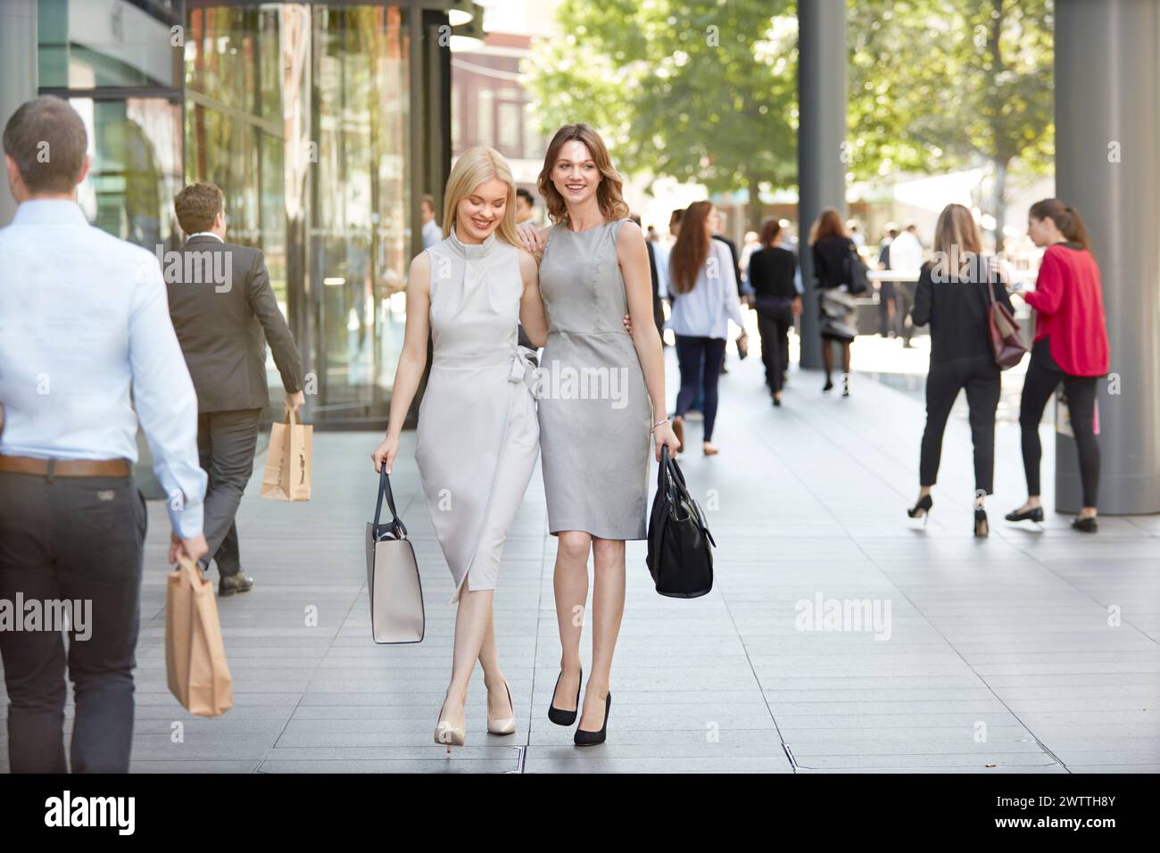 Two women walking together on a city sidewalk Stock Photo - Alamy