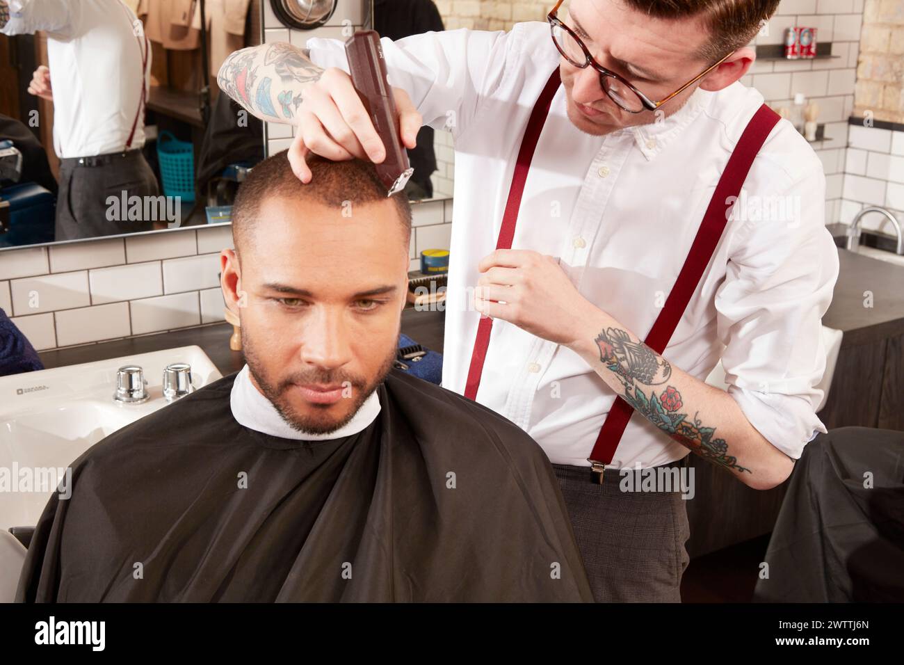 Barber giving a client a haircut Stock Photo - Alamy