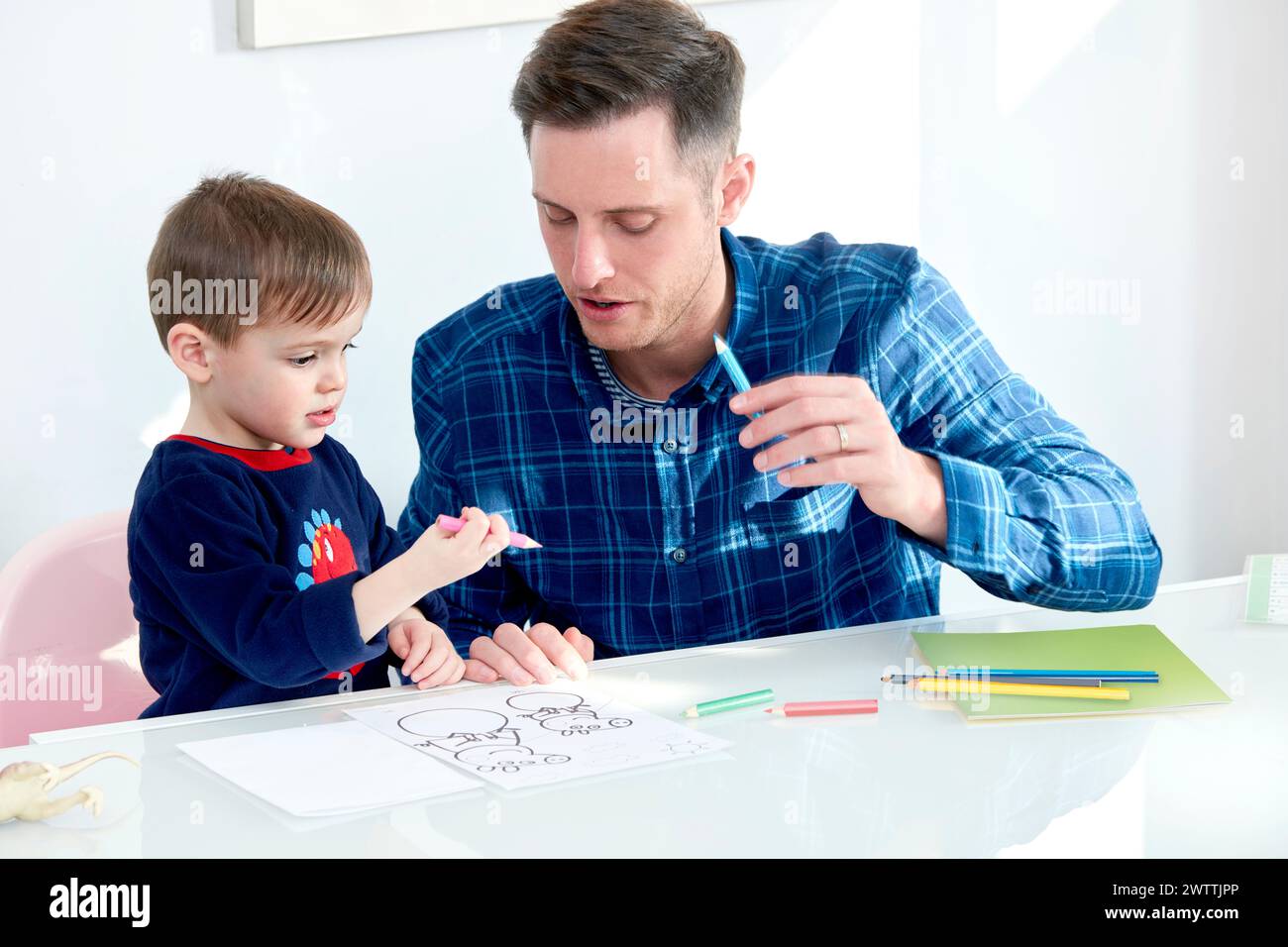 Man and child drawing together at a table Stock Photo - Alamy