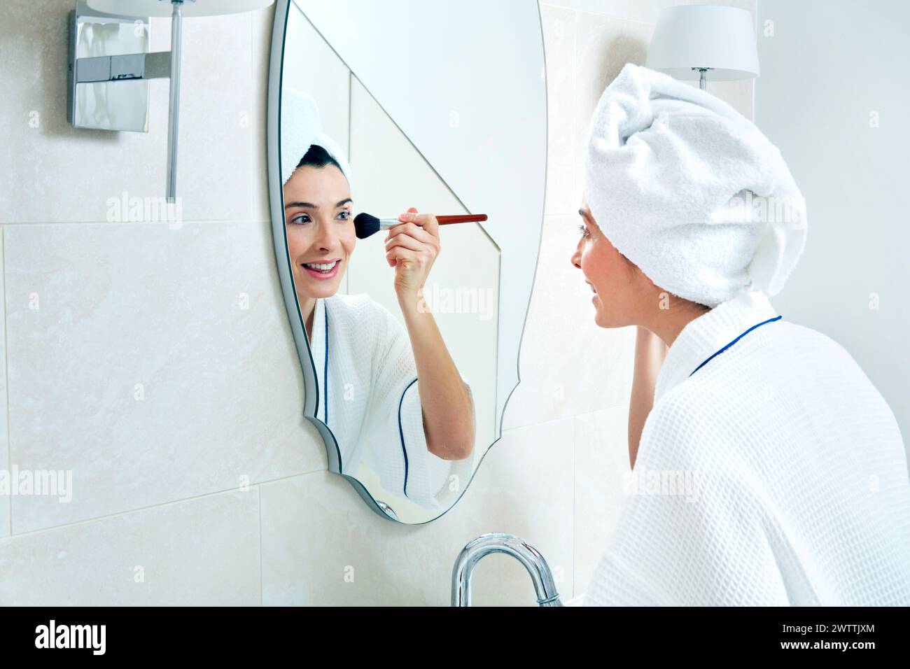 Woman applying makeup in bathroom mirror Stock Photo - Alamy