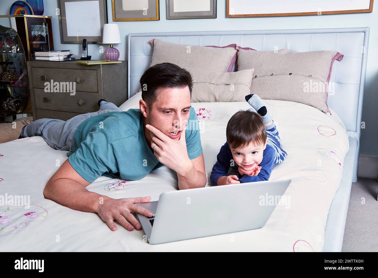 Man and child using laptop on bed Stock Photo - Alamy