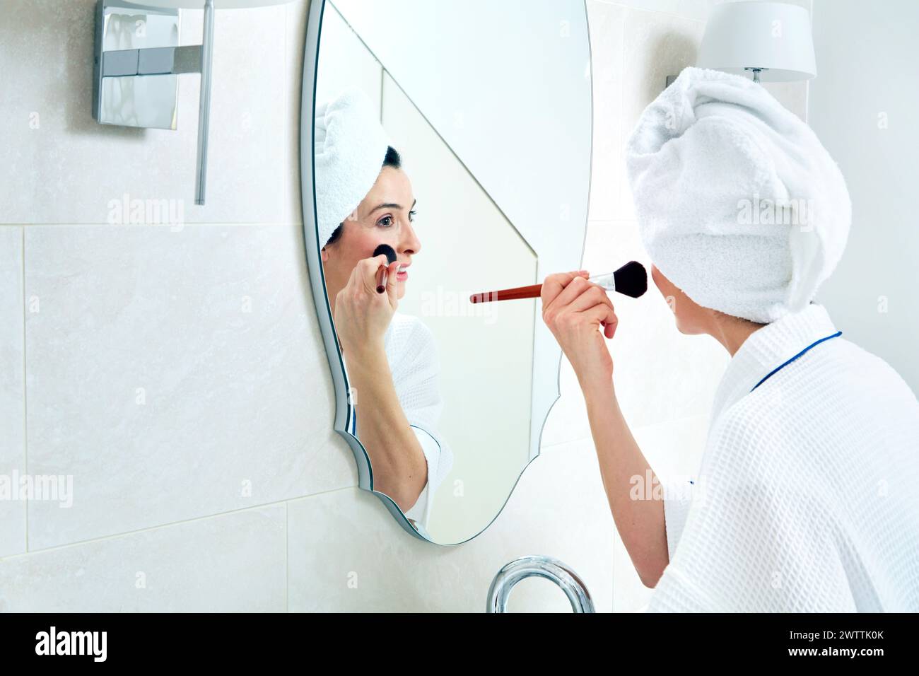 Woman applying makeup in bathroom mirror Stock Photo - Alamy