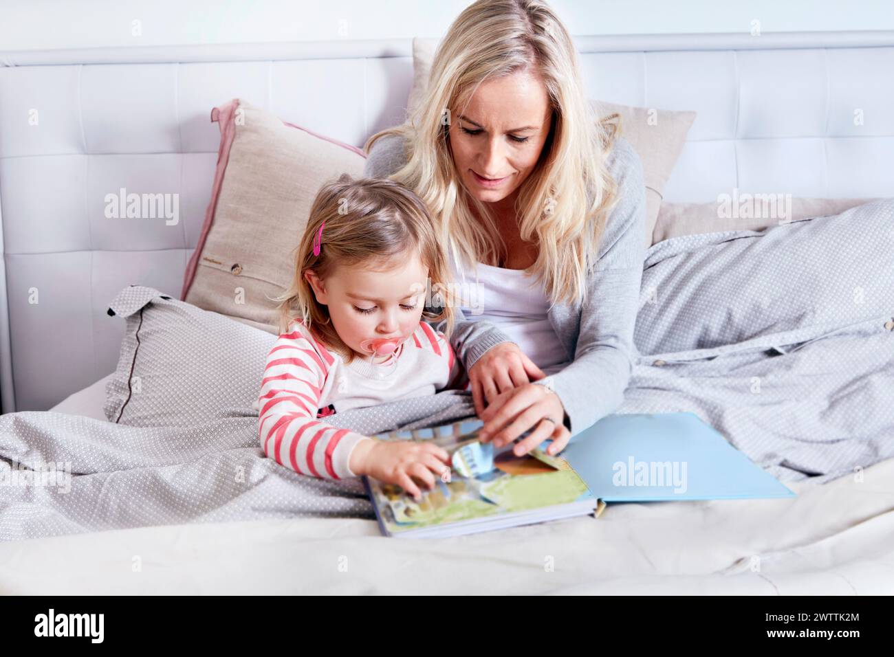 Mother and child reading a book together in bed Stock Photo - Alamy