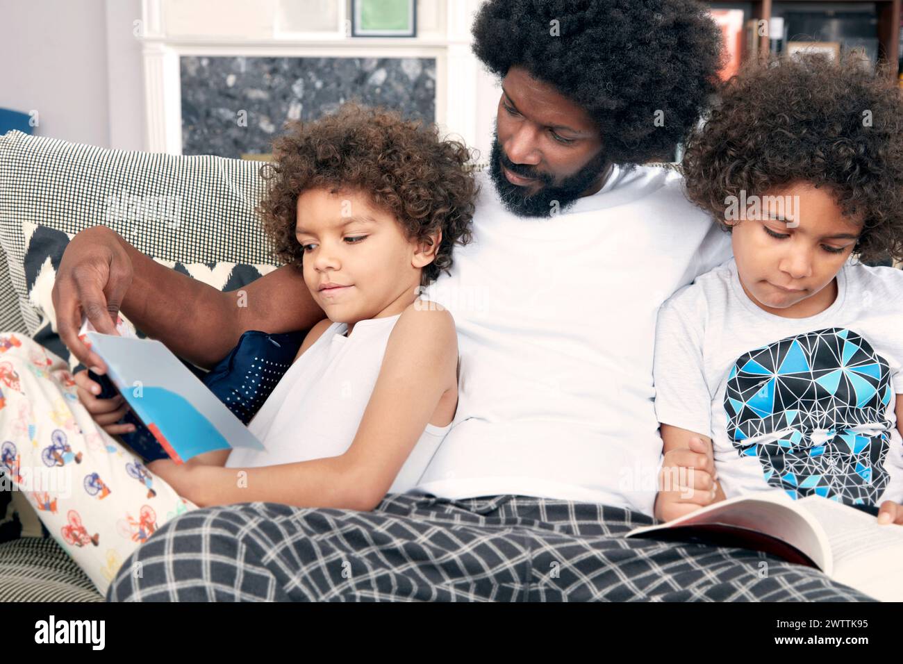Father reading a book with two children on a couch Stock Photo - Alamy