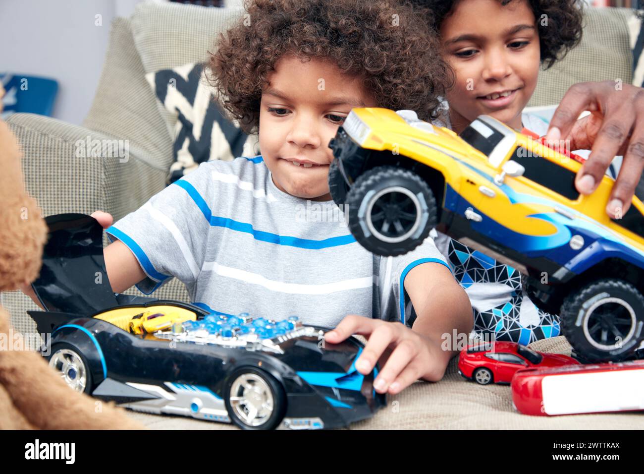 Children playing with toy cars on a couch Stock Photo - Alamy