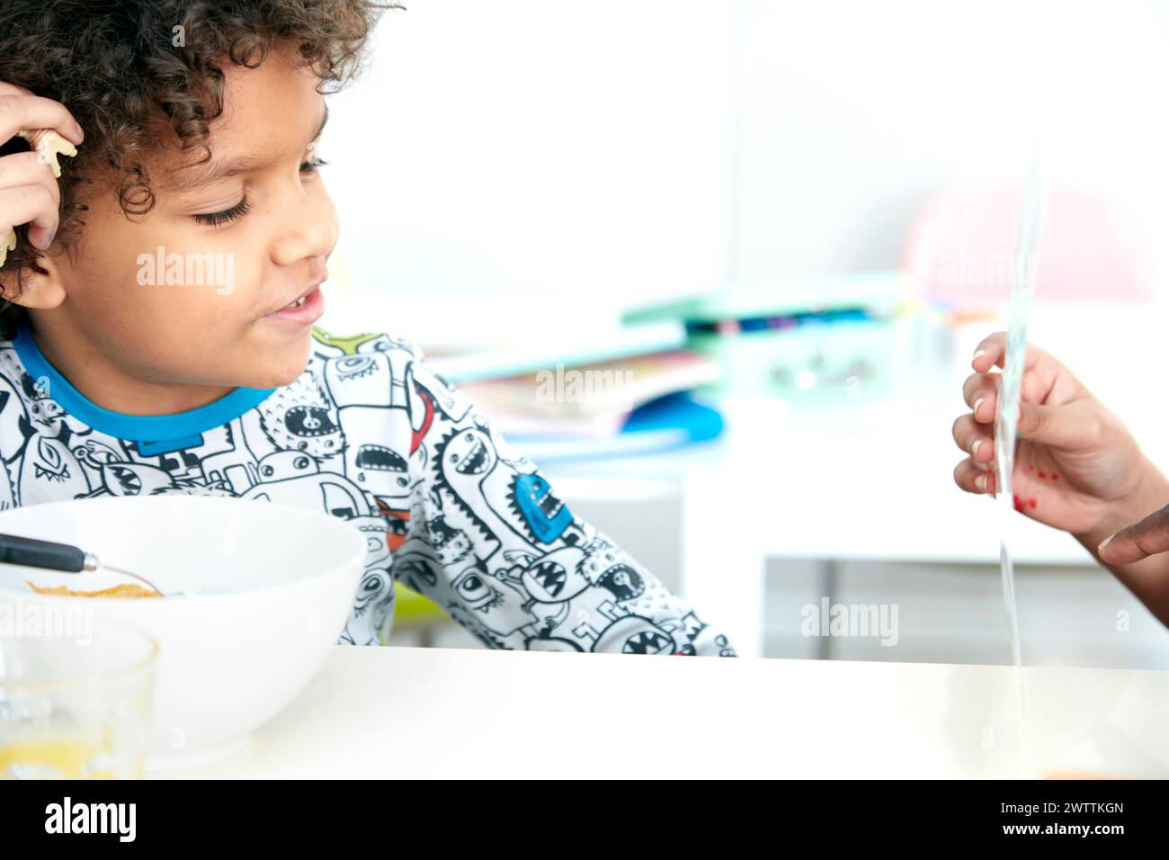 Child eating breakfast and looking at a tablet Stock Photo - Alamy
