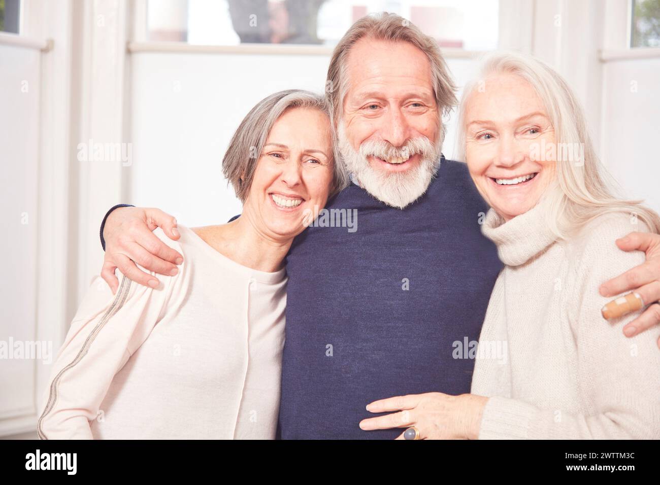 Three smiling seniors embracing indoors Stock Photo - Alamy