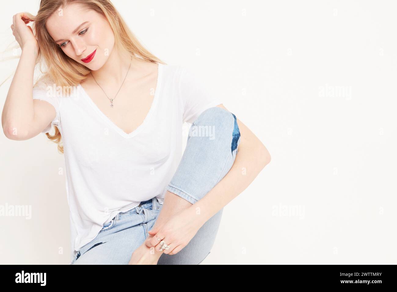 Woman posing in white top and blue jeans Stock Photo - Alamy