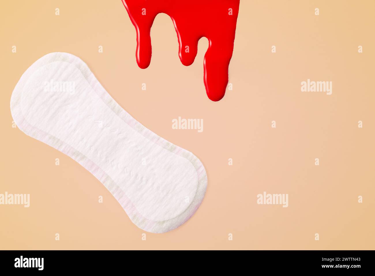 Blood and feminine hygiene pad on peach background. First menstrual ...