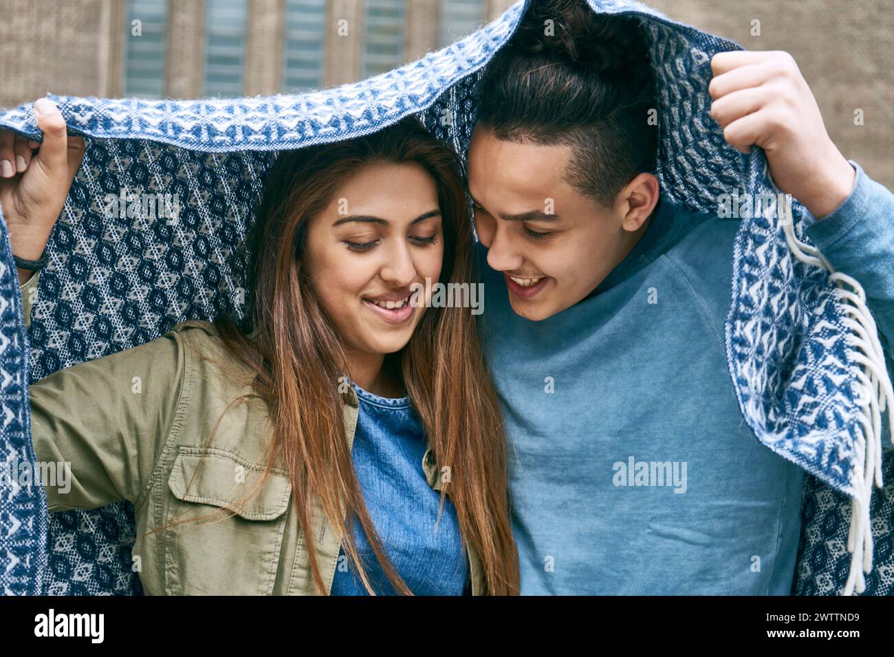 Two people smiling under a shared blanket Stock Photo - Alamy