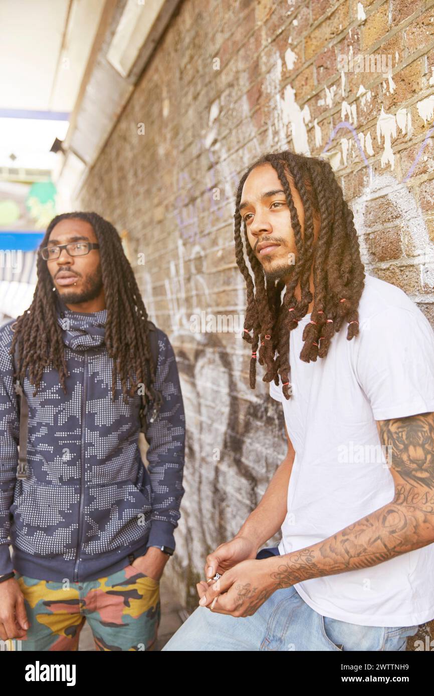 Two men with dreadlocks standing by a graffiti wall Stock Photo - Alamy
