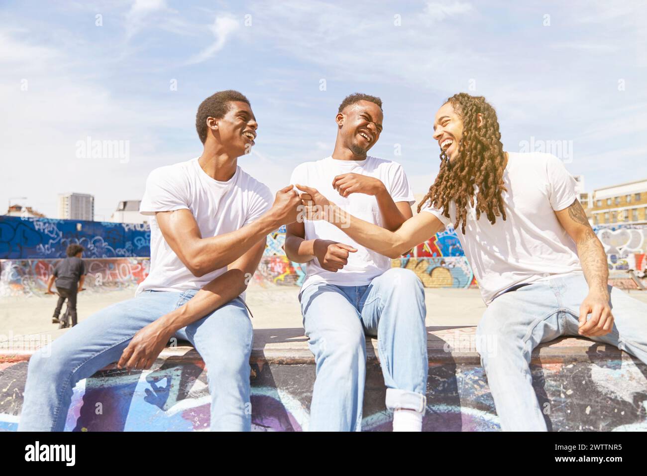 Three friends laughing and doing handshake Stock Photo - Alamy