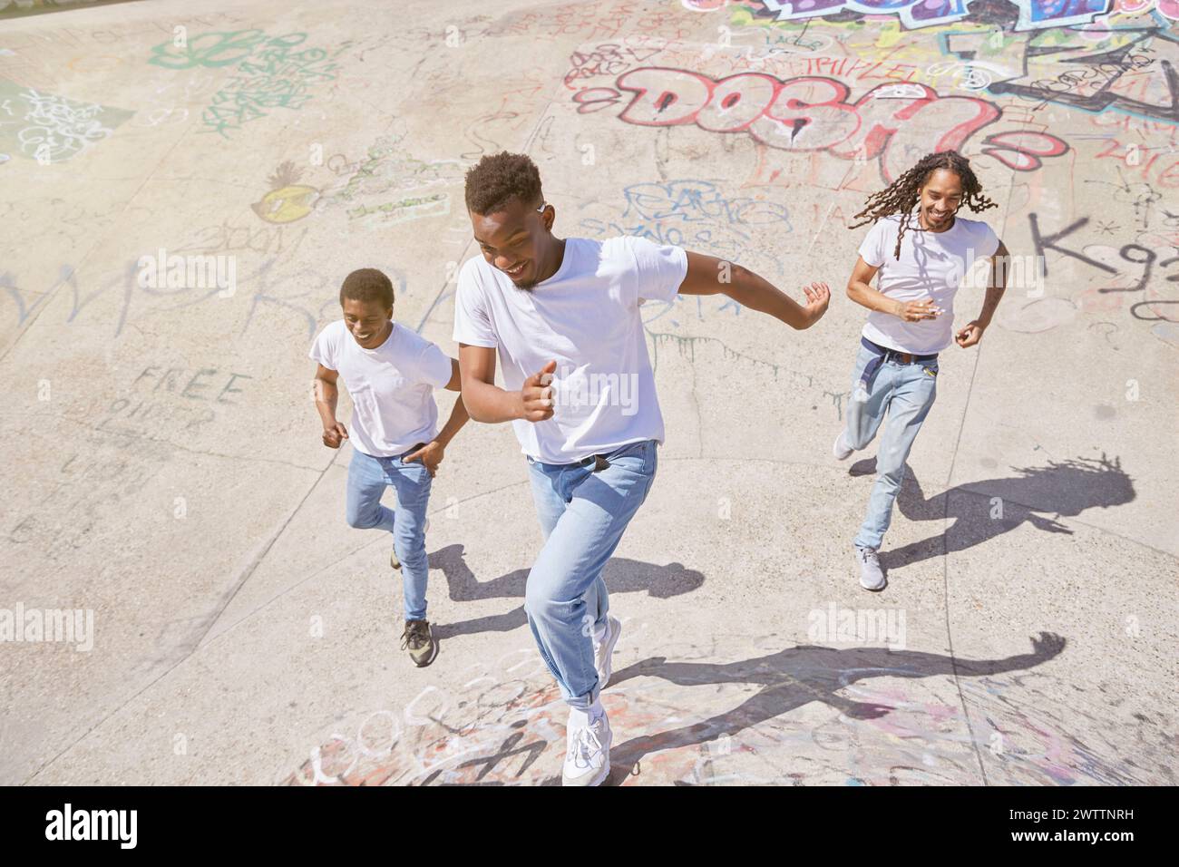 Three kids running on graffiti-covered ground Stock Photo - Alamy