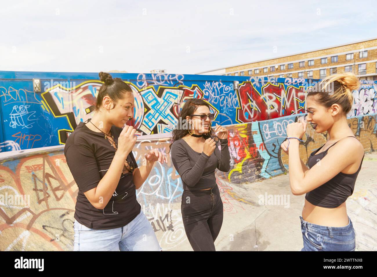 Friends sharing a light moment in front of graffiti wall Stock Photo ...