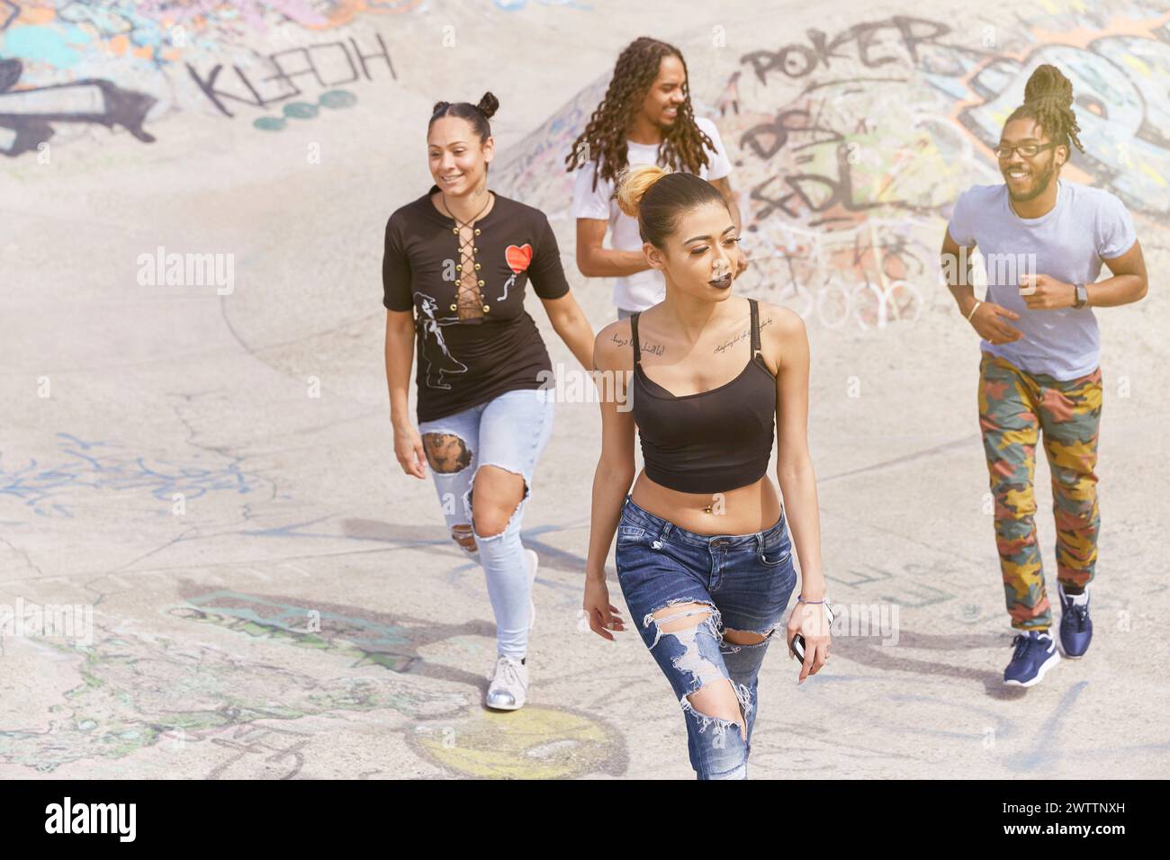 Group of young adults walking on graffiti-covered pavement Stock Photo ...