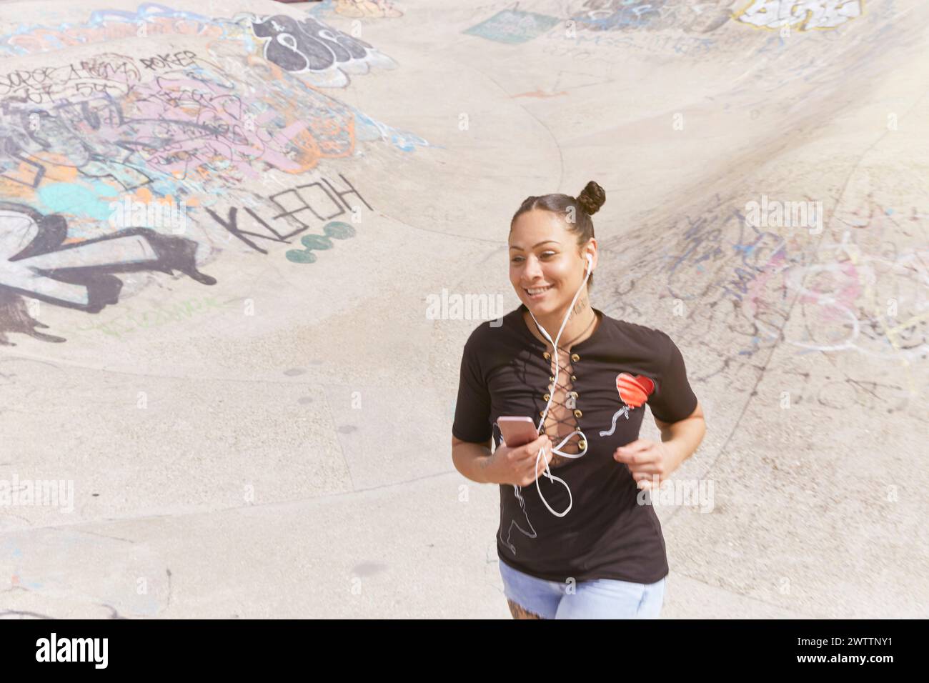 Woman running in a graffiti-covered skate park Stock Photo - Alamy