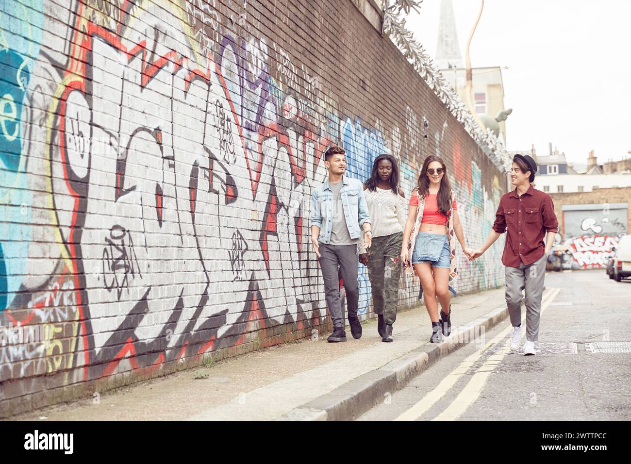 Friends walking by a graffiti wall Stock Photo - Alamy