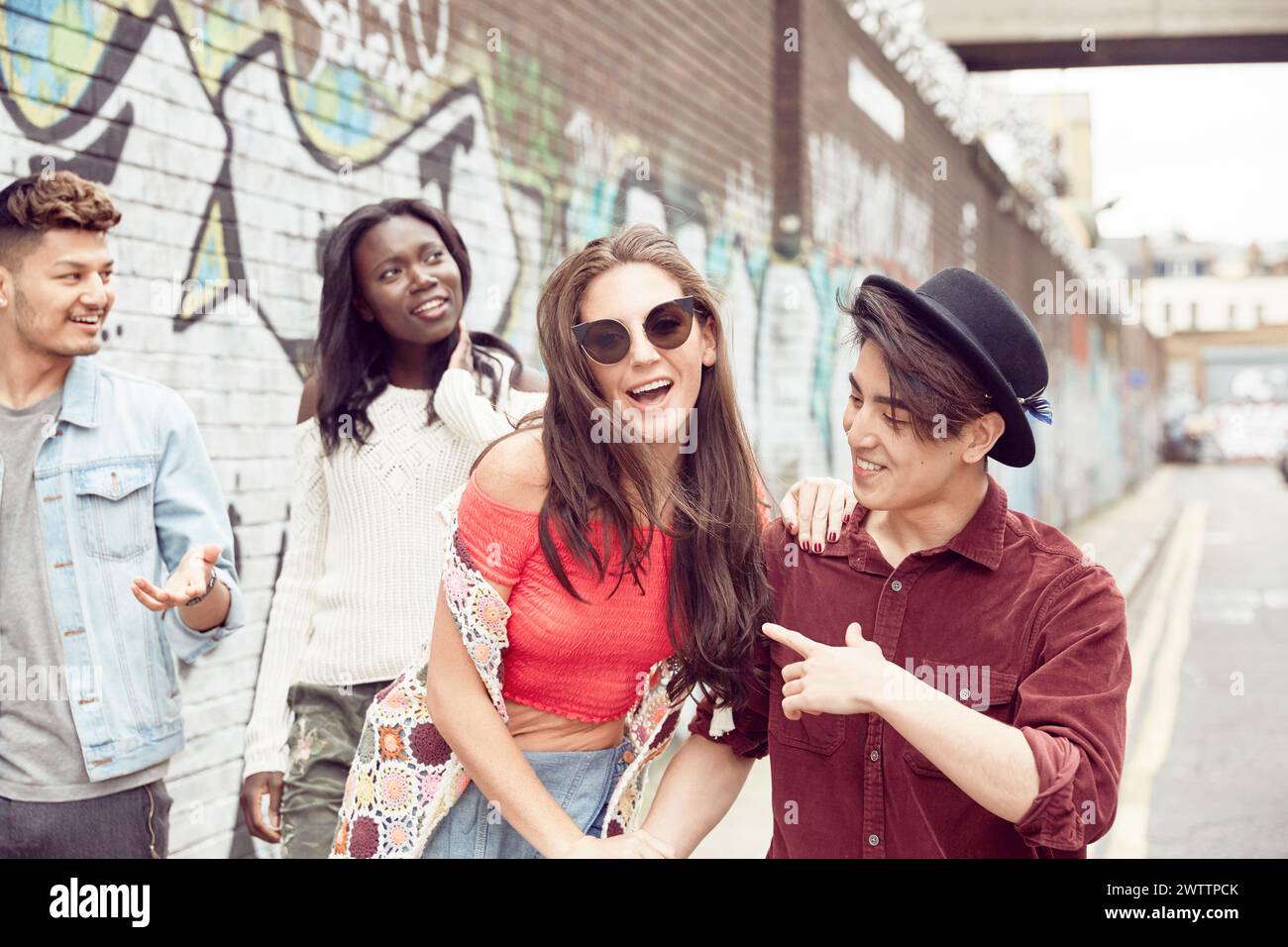 Friends laughing and walking by graffiti wall Stock Photo - Alamy
